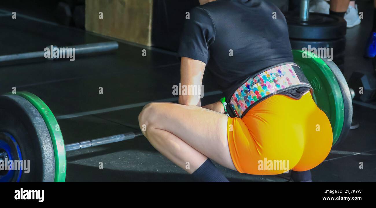One women squatting at the start of performing a clean with heavy ...