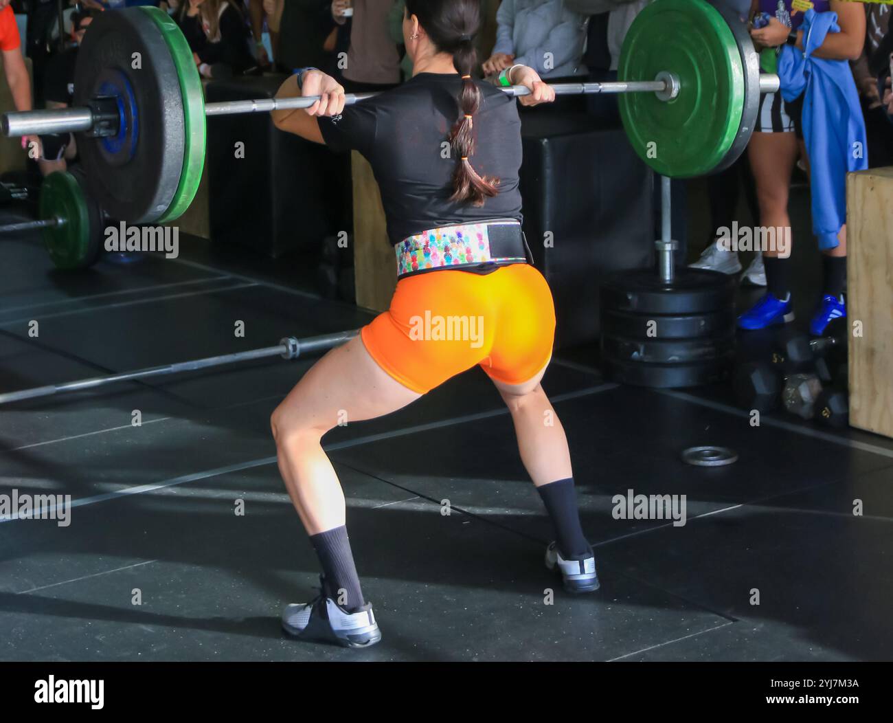 Rear view of one Women performing a clean while lifting heavy weights ...