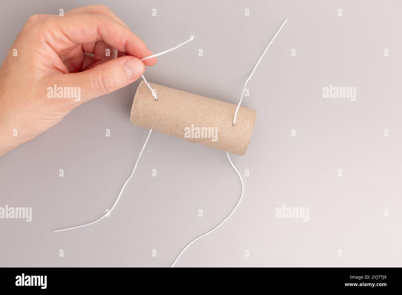 hand is holding toilet paper cardboard roll tube while the other hand ...