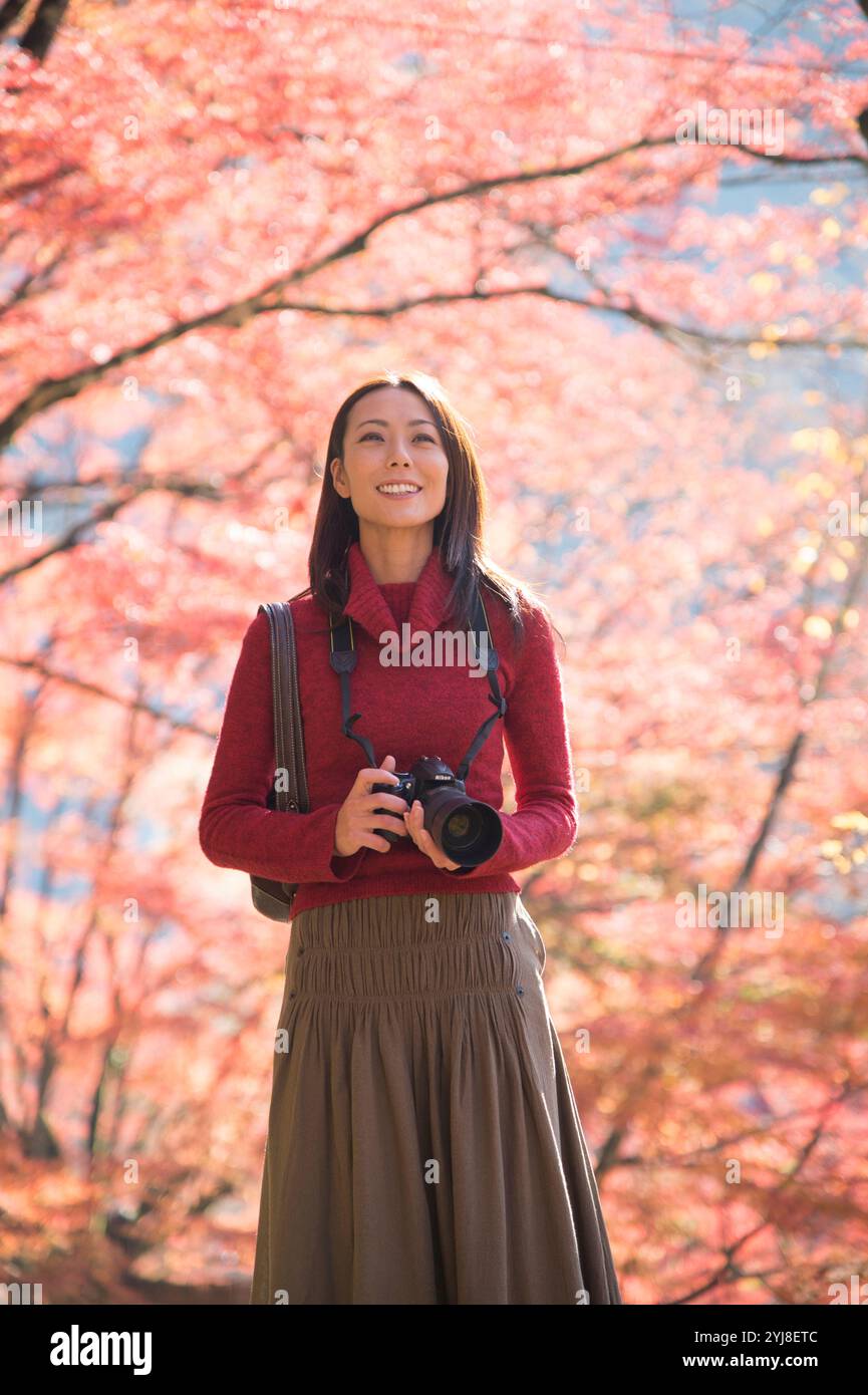 Woman taking photos of autumn leaves with a camera Stock Photo - Alamy