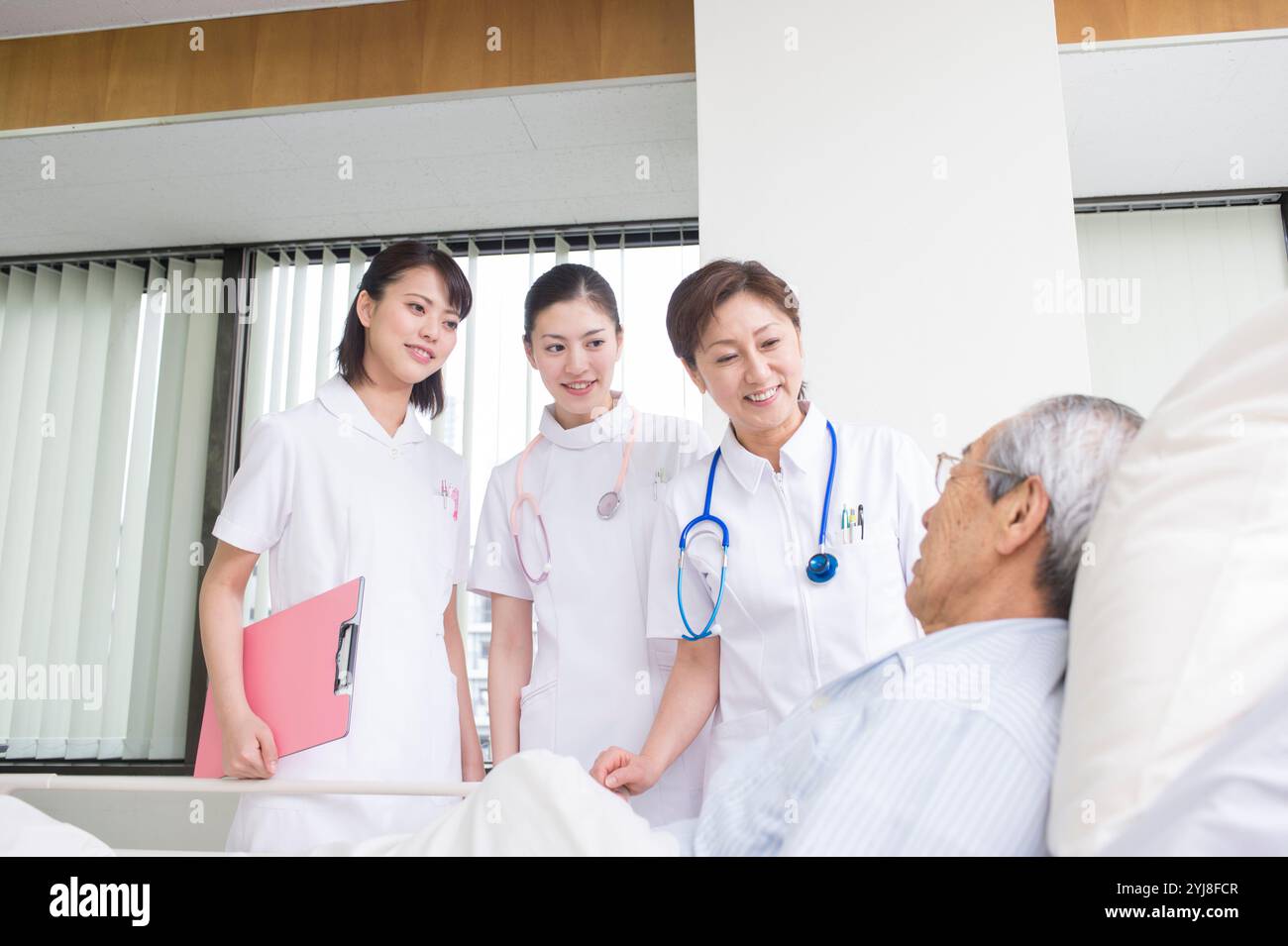 Female doctor and nurse examining a hospitalised senior patient in bed ...