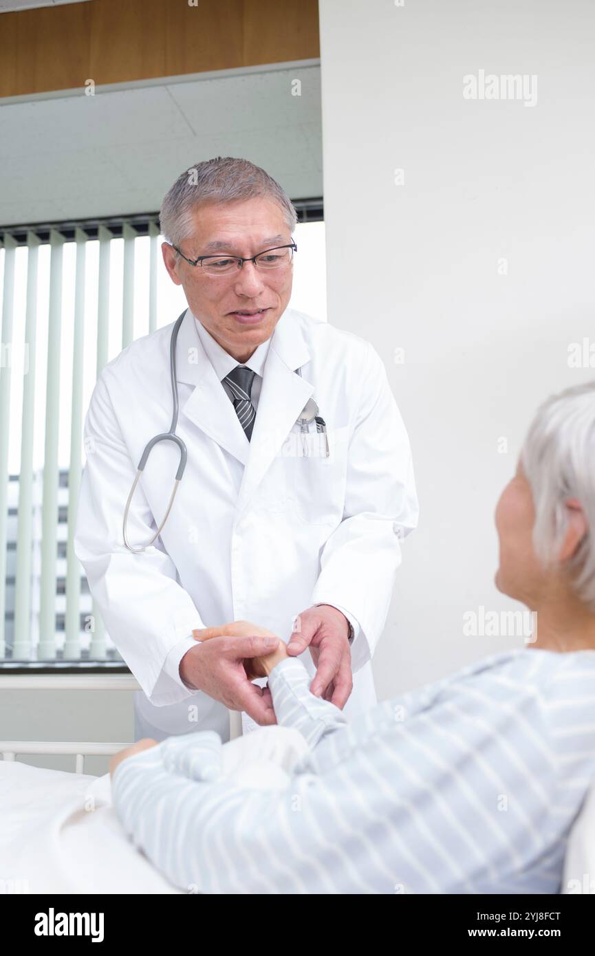 Doctor examining a hospitalised senior female patient in bed Stock ...