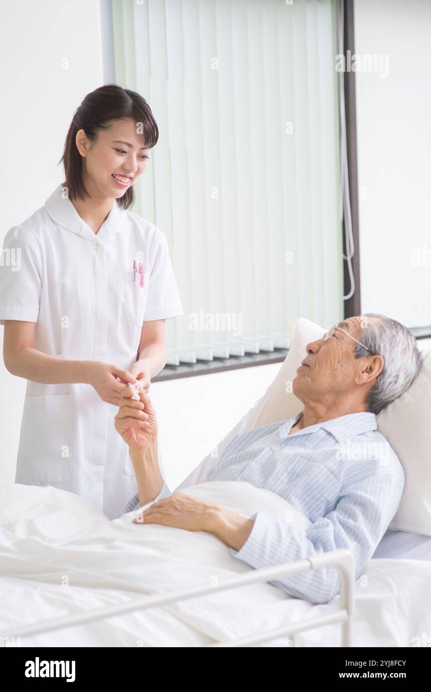 Nurse giving thermometer to hospitalised senior patient in bed Stock ...