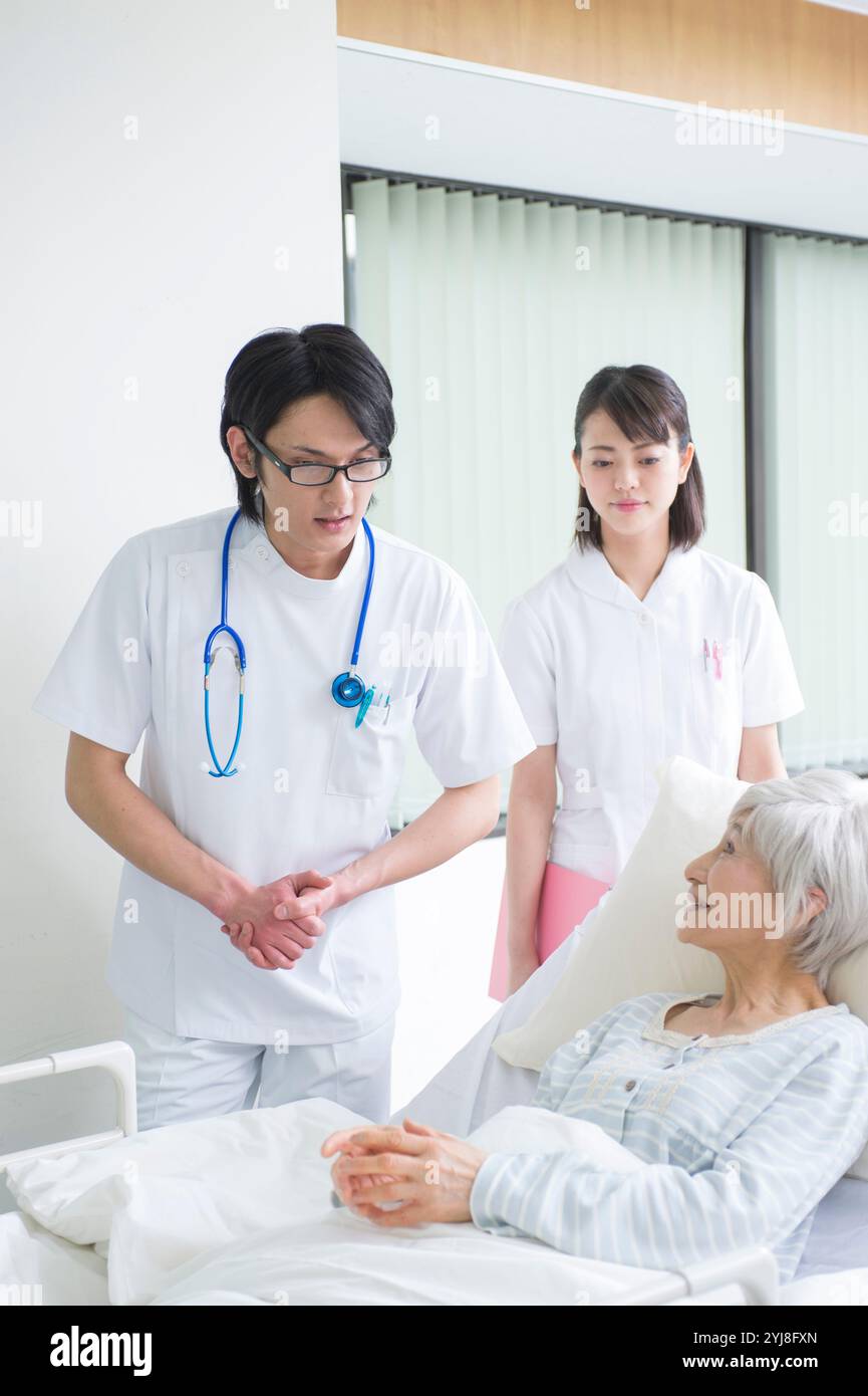 Doctor and nurse examining a hospitalised senior female patient in bed ...