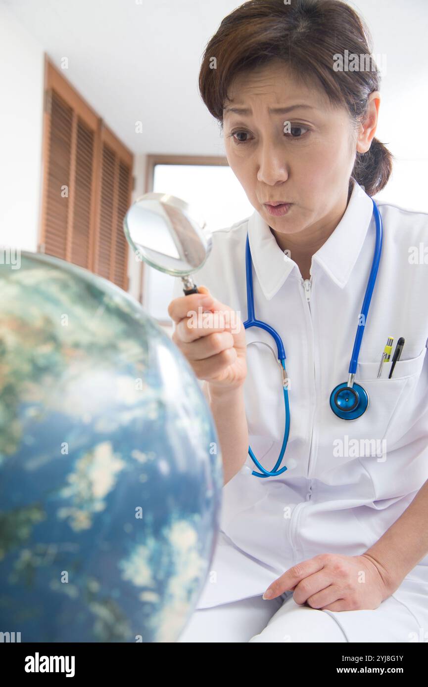 Female doctor looking at globe through magnifying glass Stock Photo - Alamy