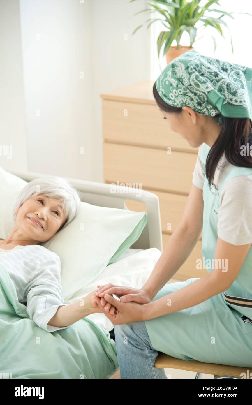 Care helper holding the hand of the elderly person in the care bed ...