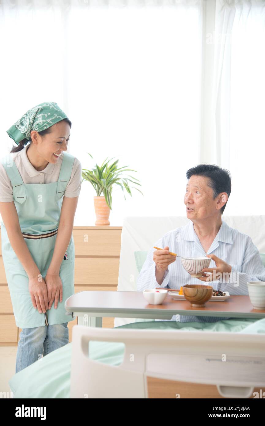 Care helper feeding an elderly person in a care bed Stock Photo - Alamy