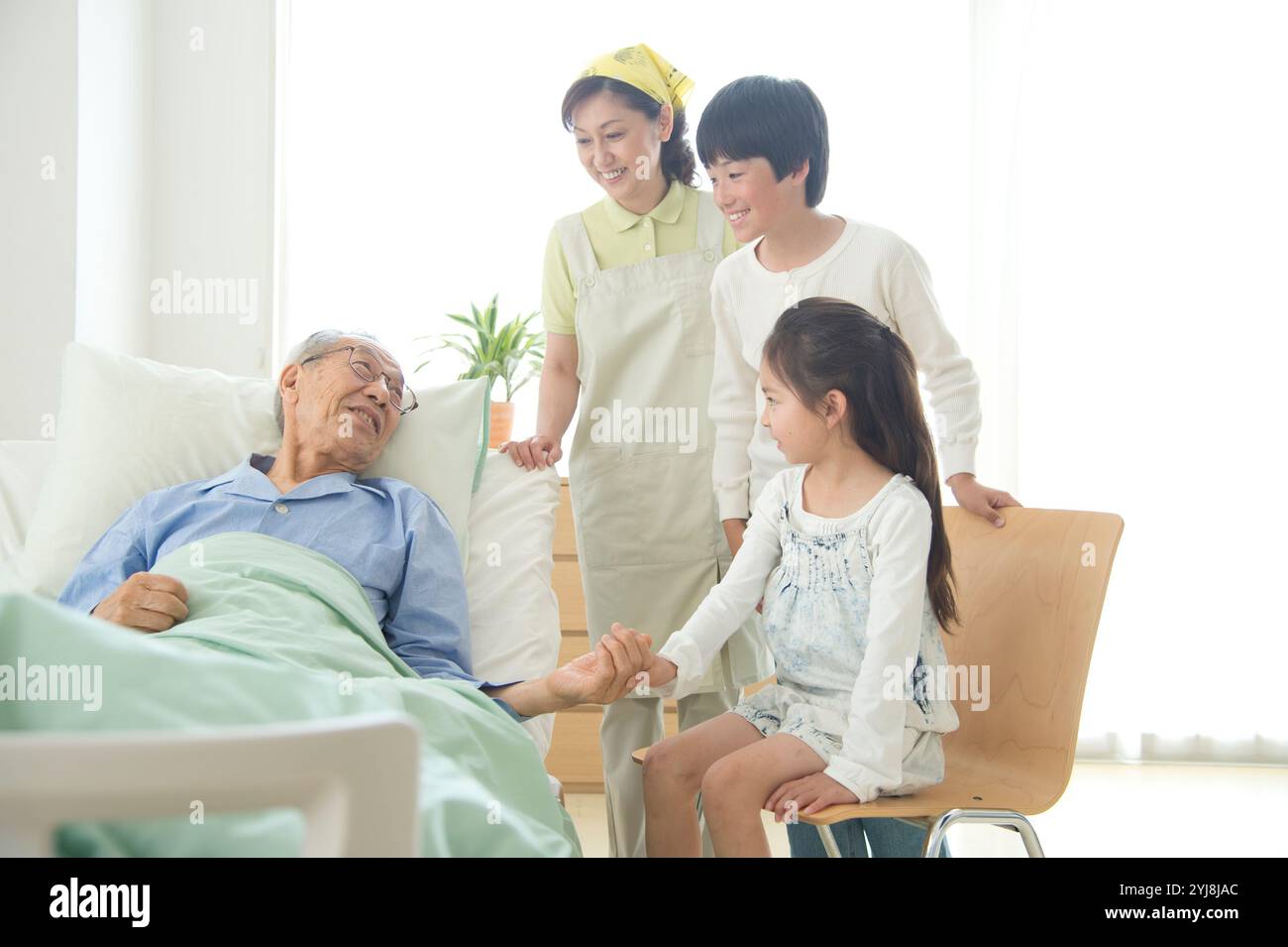 Care helper with elderly person in care bed and grandson Stock Photo ...