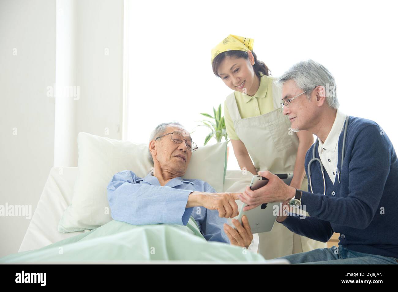 Doctor and care helper examining an elderly person in a care bed Stock ...