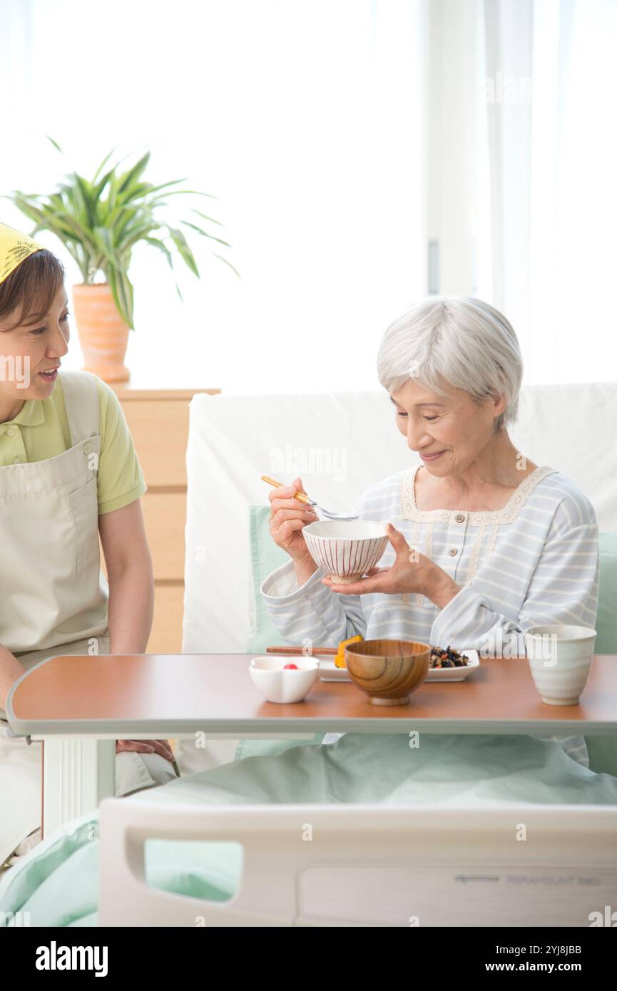 Care helper feeding an elderly person in a care bed Stock Photo - Alamy