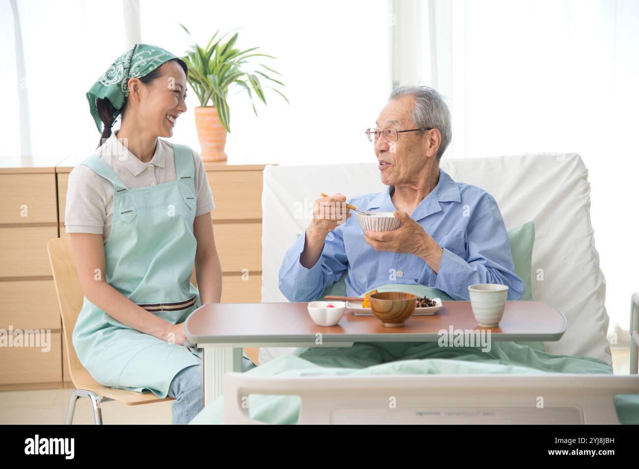Care helper feeding an elderly person in a care bed Stock Photo - Alamy