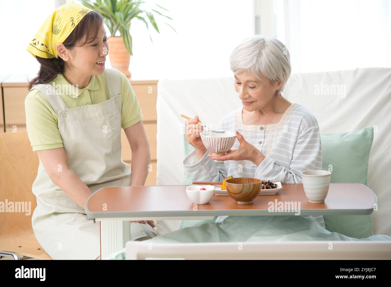 Care helper feeding an elderly person in a care bed Stock Photo - Alamy