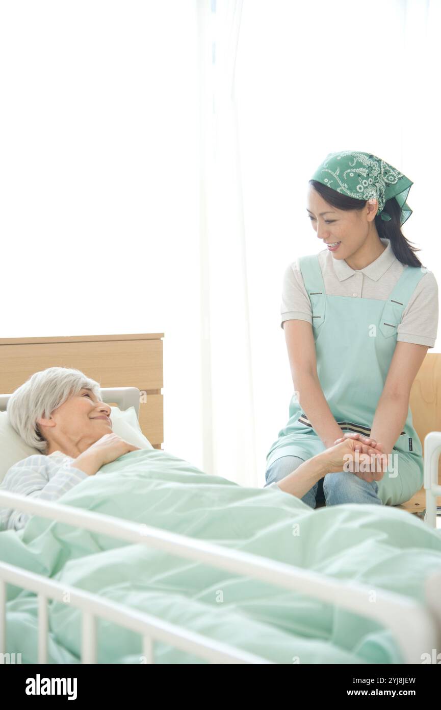 Care helper holding the hand of the elderly person in the care bed ...