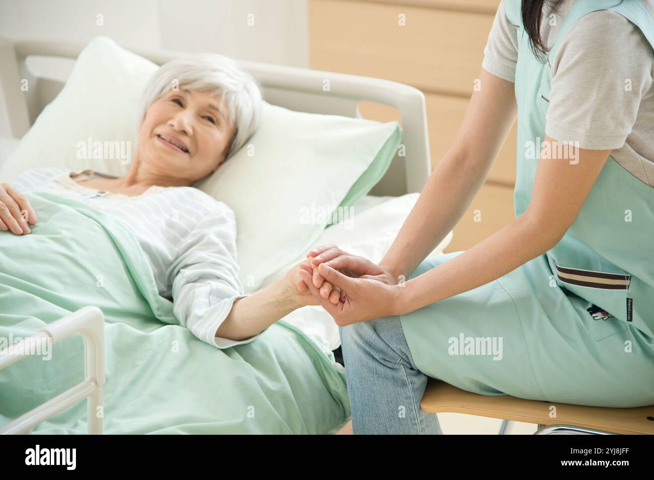 Care helper holding the hand of the elderly person in the care bed ...
