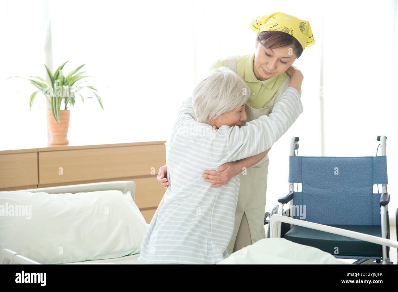 Care helper placing elderly person in care bed in wheelchair Stock ...