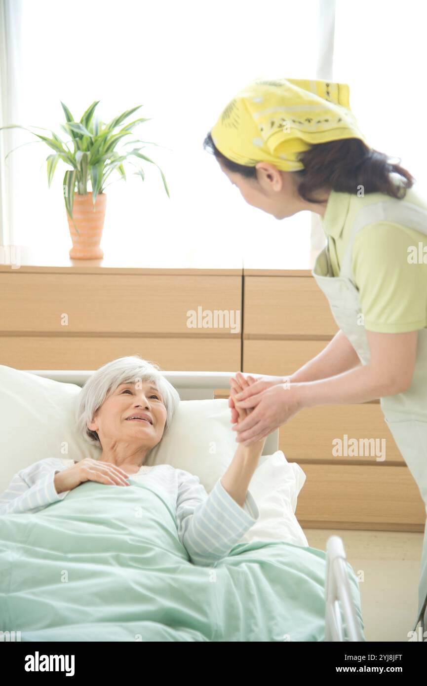 Care helper holding the hand of the elderly person in the care bed ...
