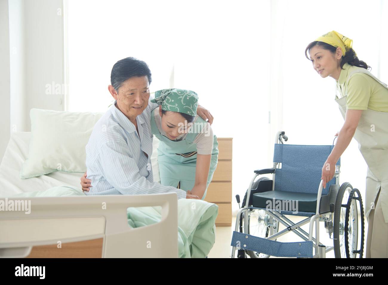 Care helper placing elderly person in care bed in wheelchair Stock ...