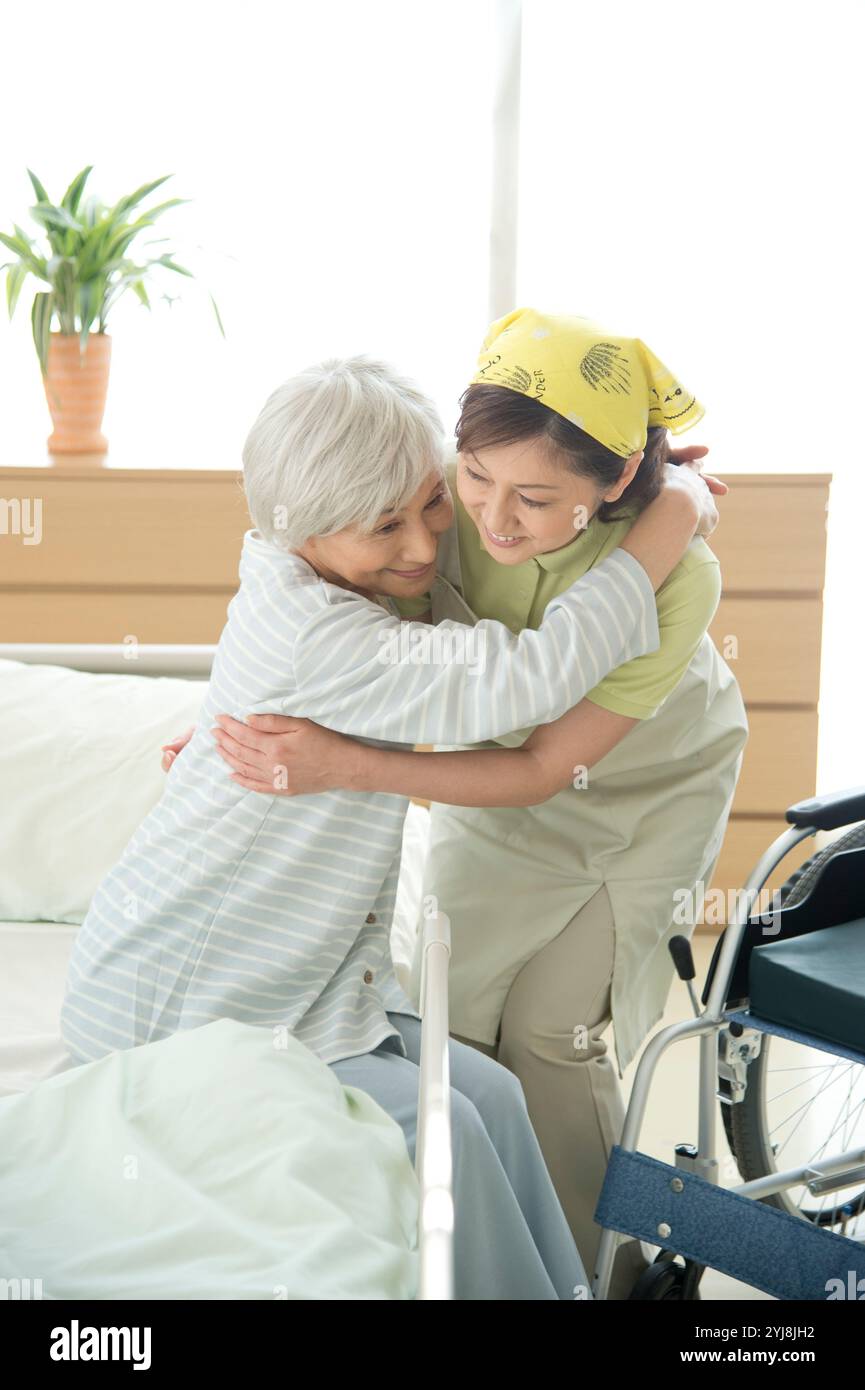 Care helper placing elderly person in care bed in wheelchair Stock ...