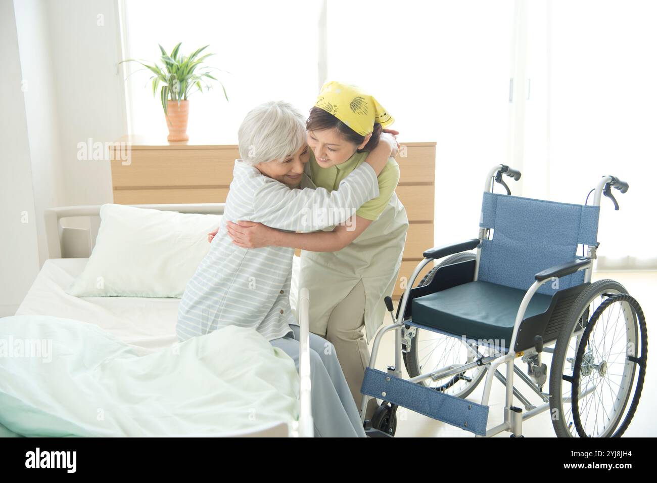 Care helper placing elderly person in care bed in wheelchair Stock ...