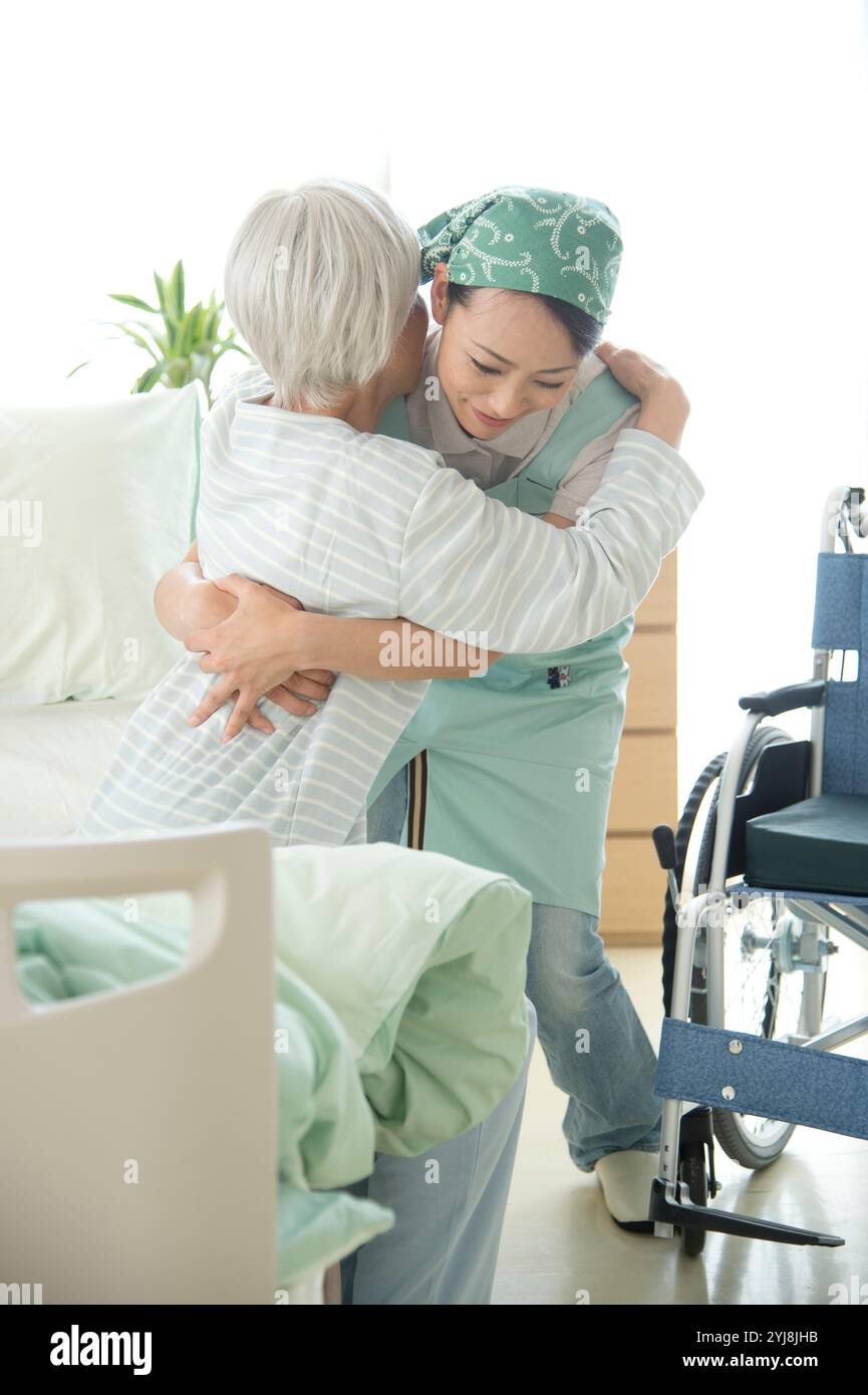 Care helper placing elderly person in care bed in wheelchair Stock ...