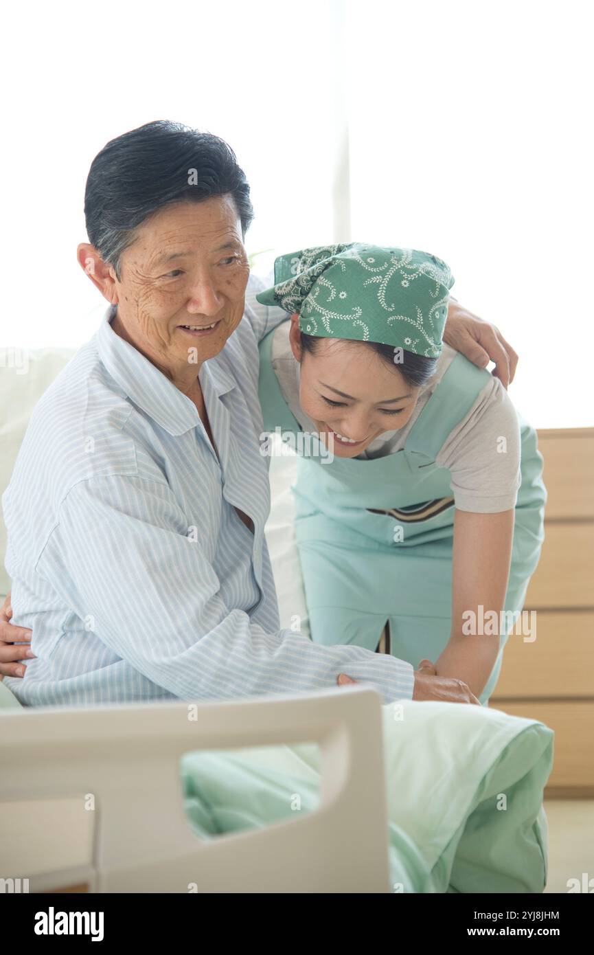 Care helper placing elderly person in care bed in wheelchair Stock ...