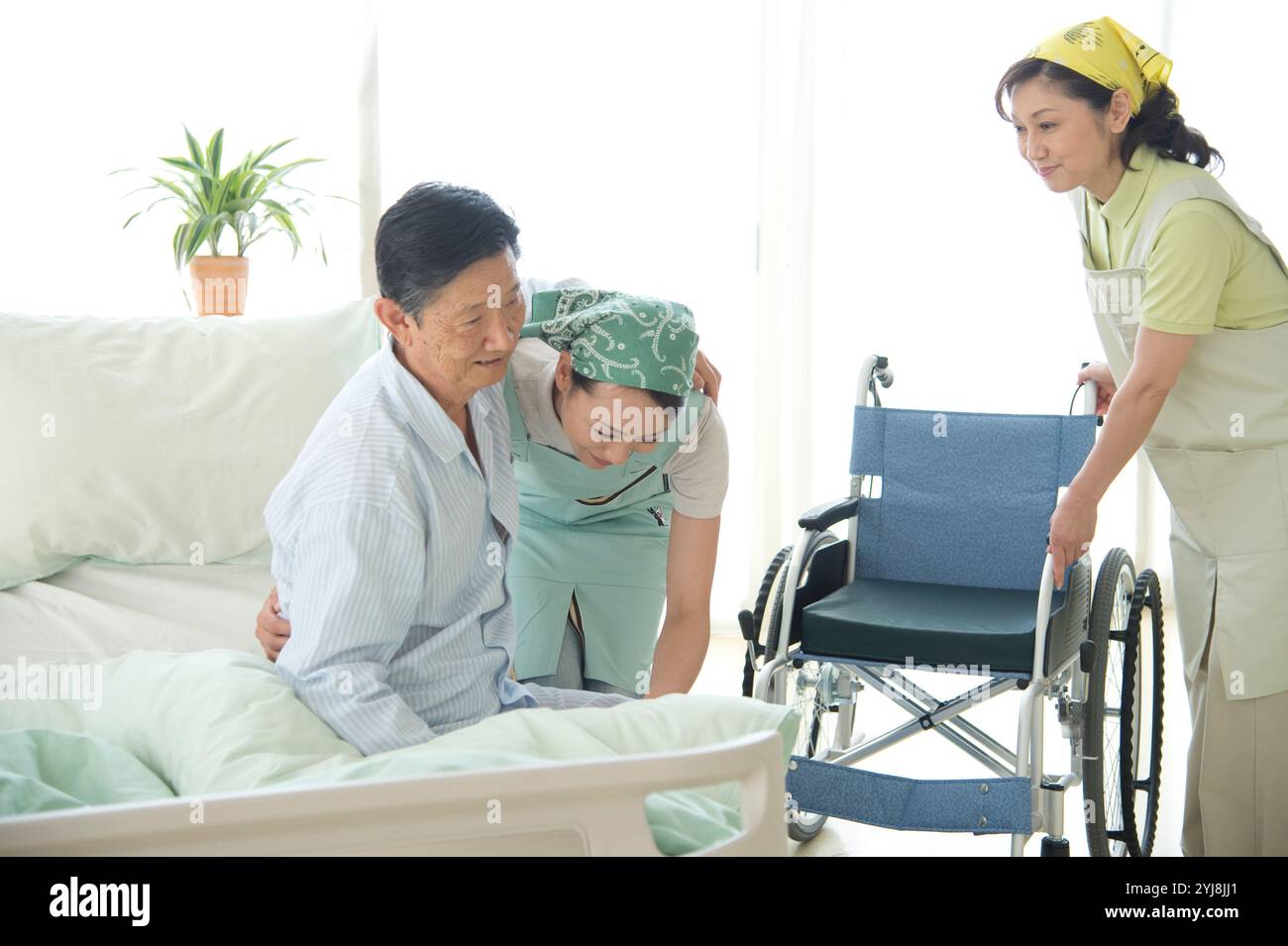 Care helper placing elderly person in care bed in wheelchair Stock ...