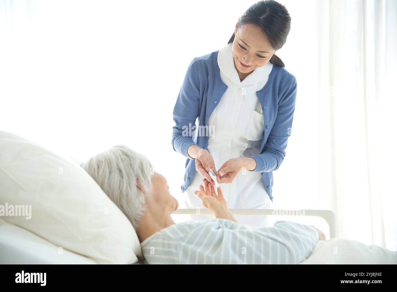 Nurse giving thermometer to hospital-bed old man Stock Photo - Alamy