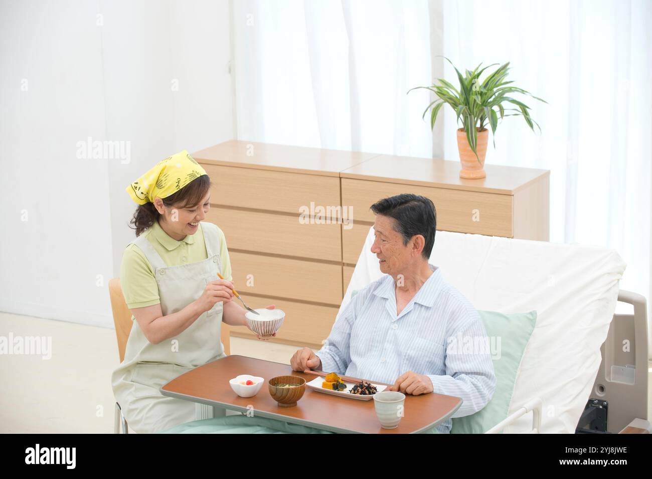 Care helper feeding an elderly person in a care bed Stock Photo - Alamy