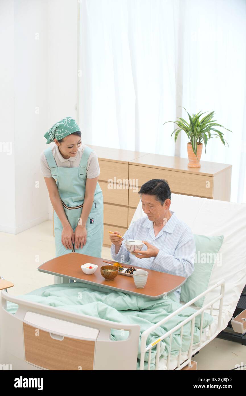 Care helper feeding an elderly person in a care bed Stock Photo - Alamy