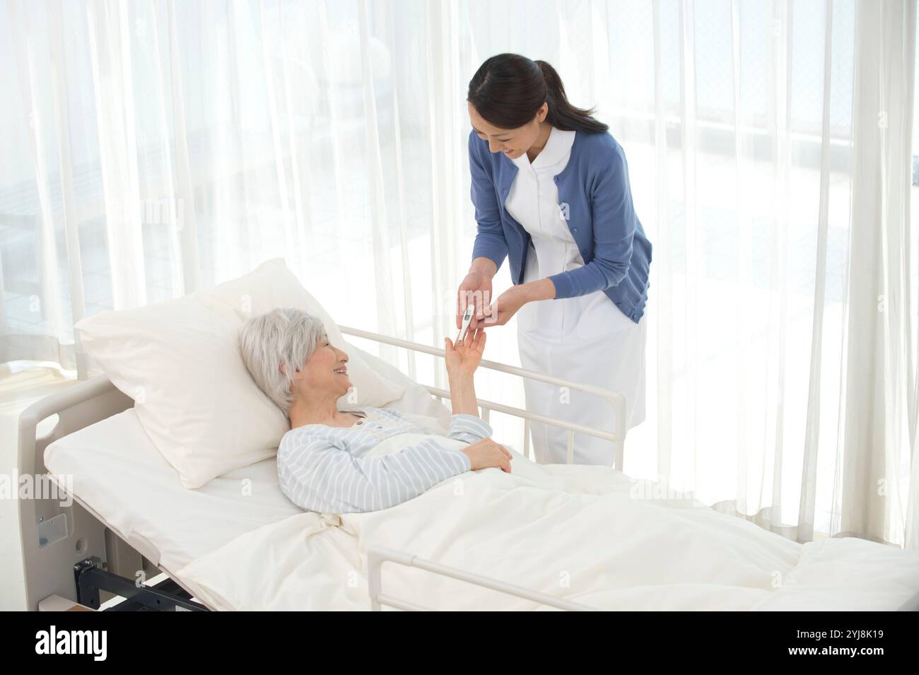 Nurse giving thermometer to hospital-bed old man Stock Photo - Alamy