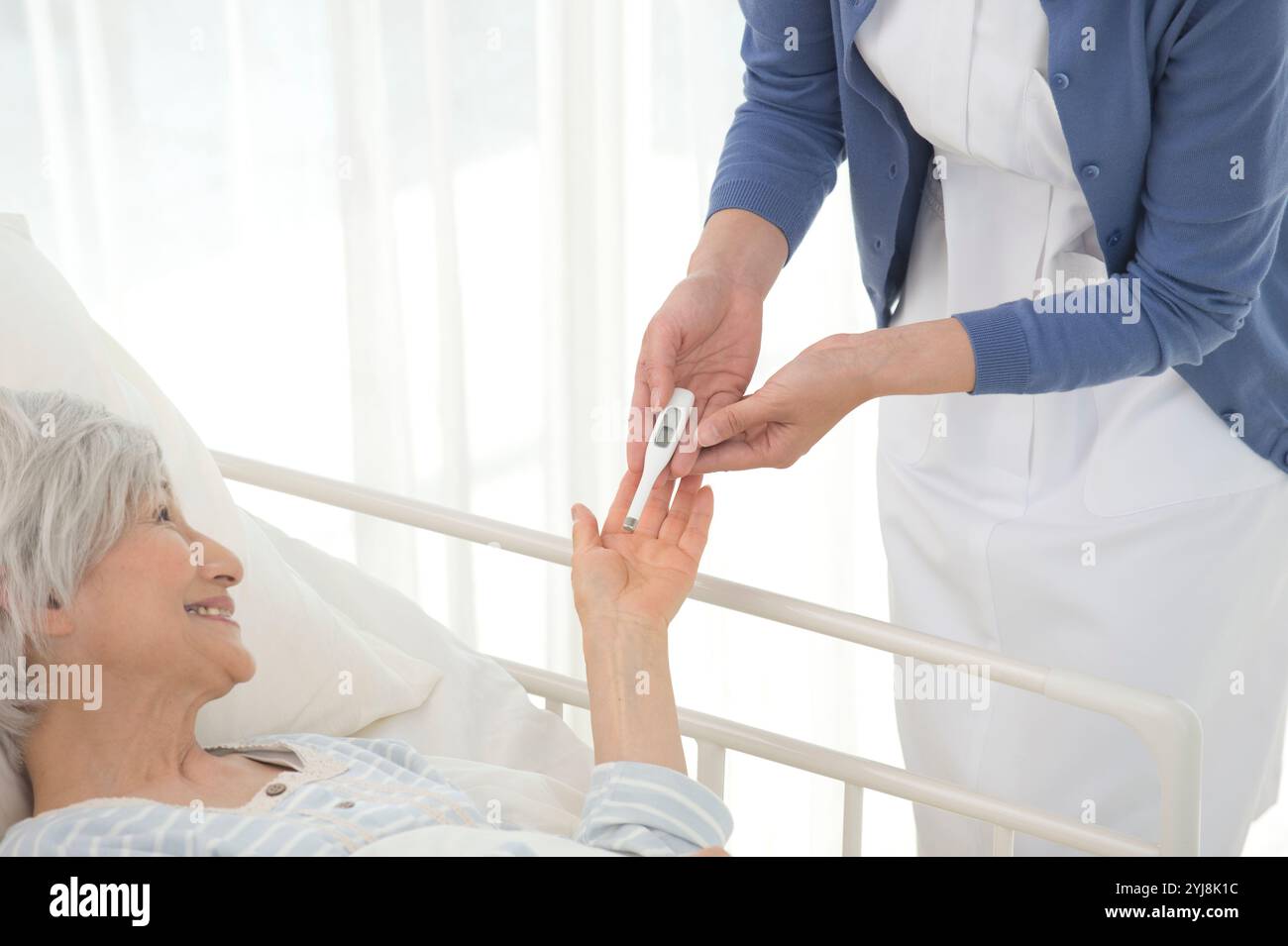 Nurse giving thermometer to hospital-bed old man Stock Photo - Alamy