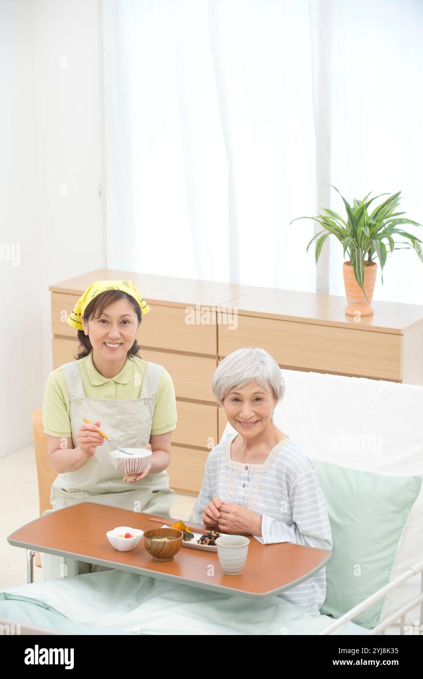 Care helper feeding an elderly person in a care bed Stock Photo - Alamy