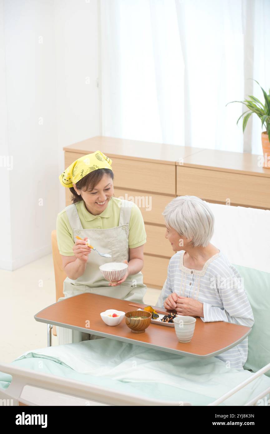 Care helper feeding an elderly person in a care bed Stock Photo - Alamy