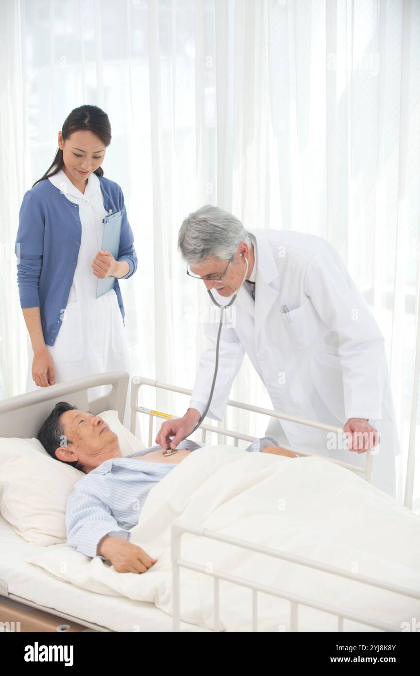 Doctor and nurse examining old man in hospital bed Stock Photo - Alamy