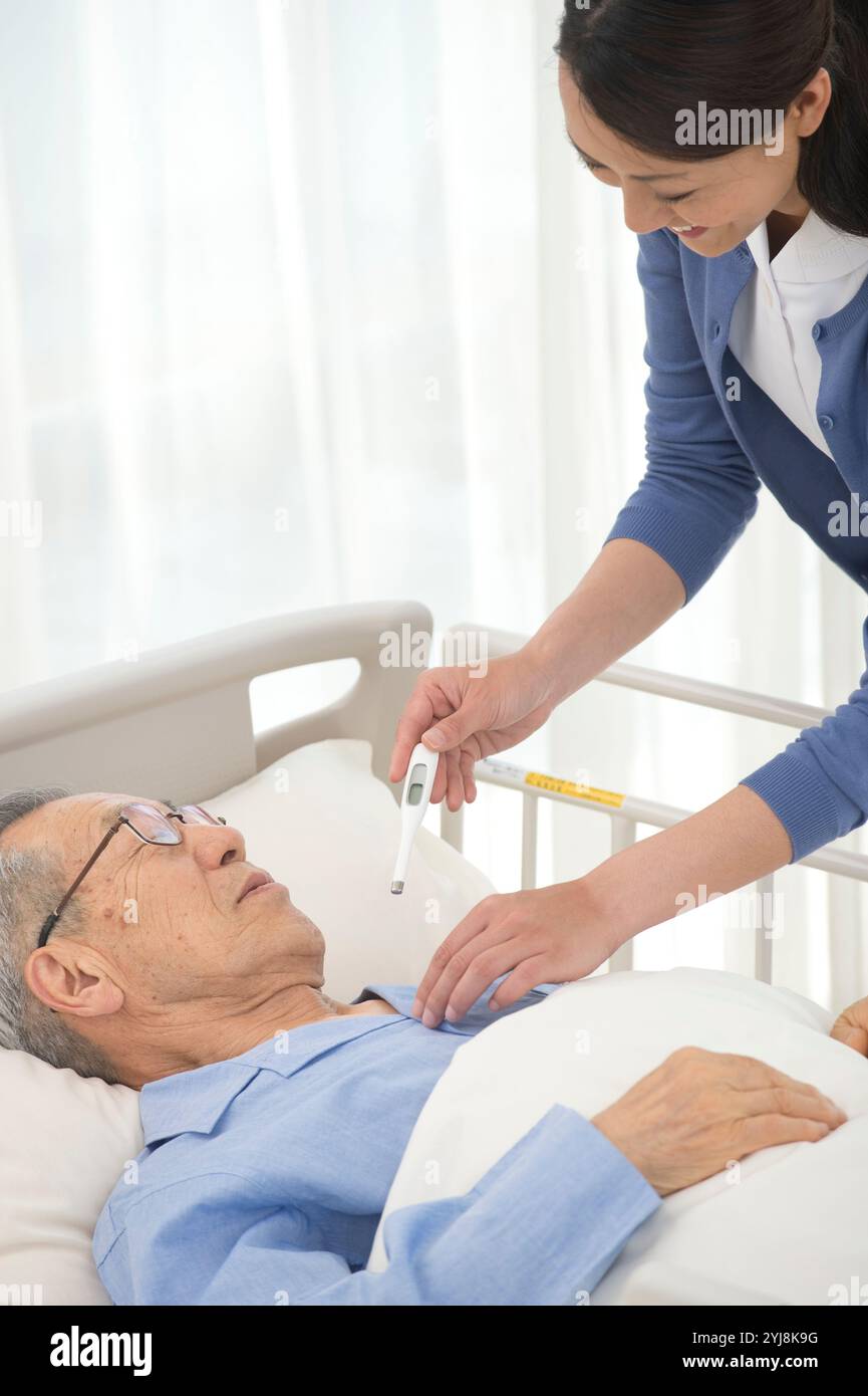 Nurse giving thermometer to hospital-bed old man Stock Photo - Alamy