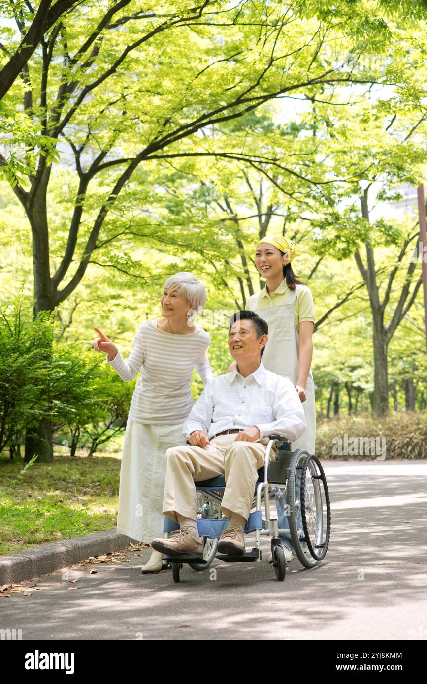 Elderly couple in wheelchair and care helper Stock Photo - Alamy