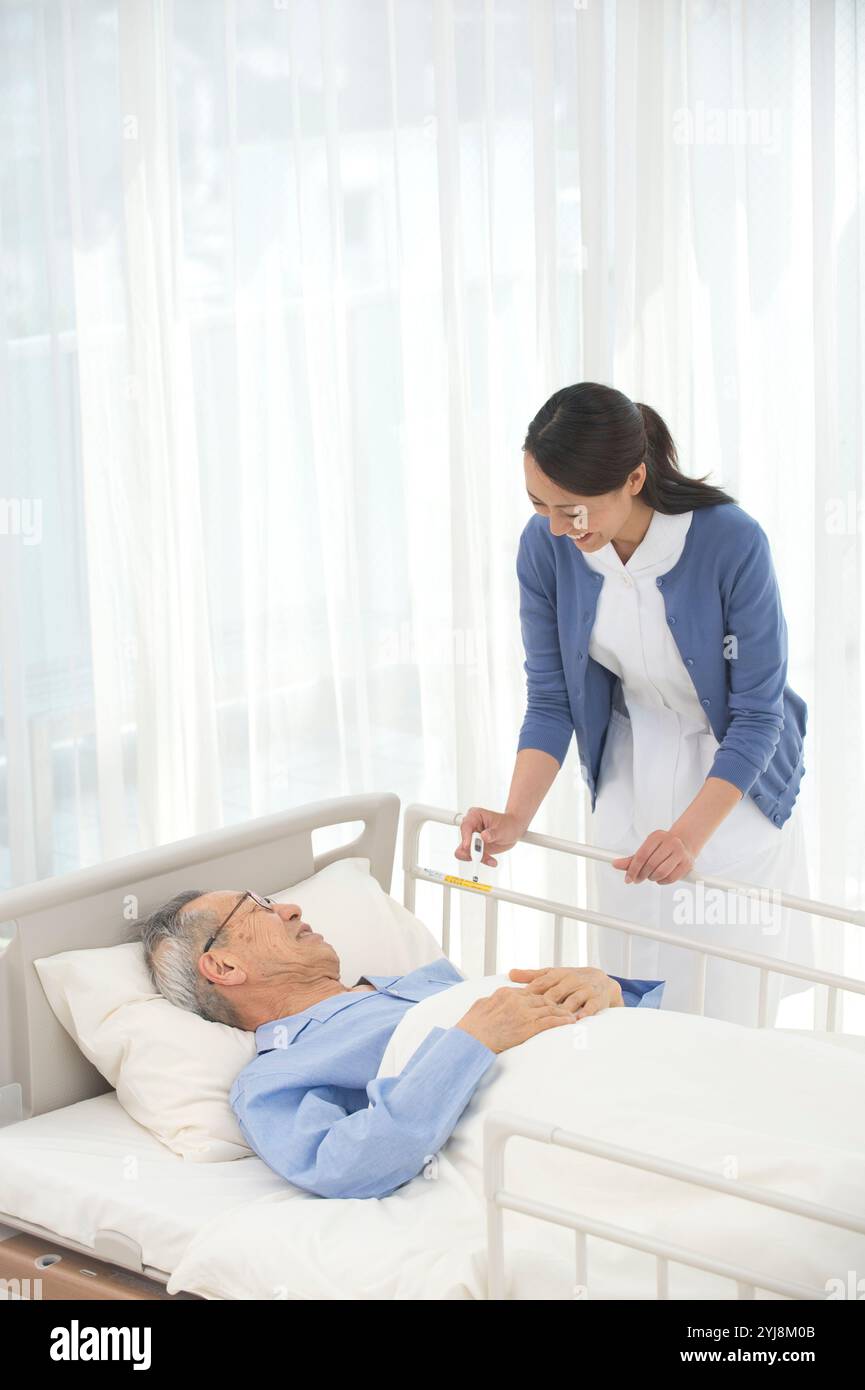 Nurse giving thermometer to hospital-bed old man Stock Photo - Alamy
