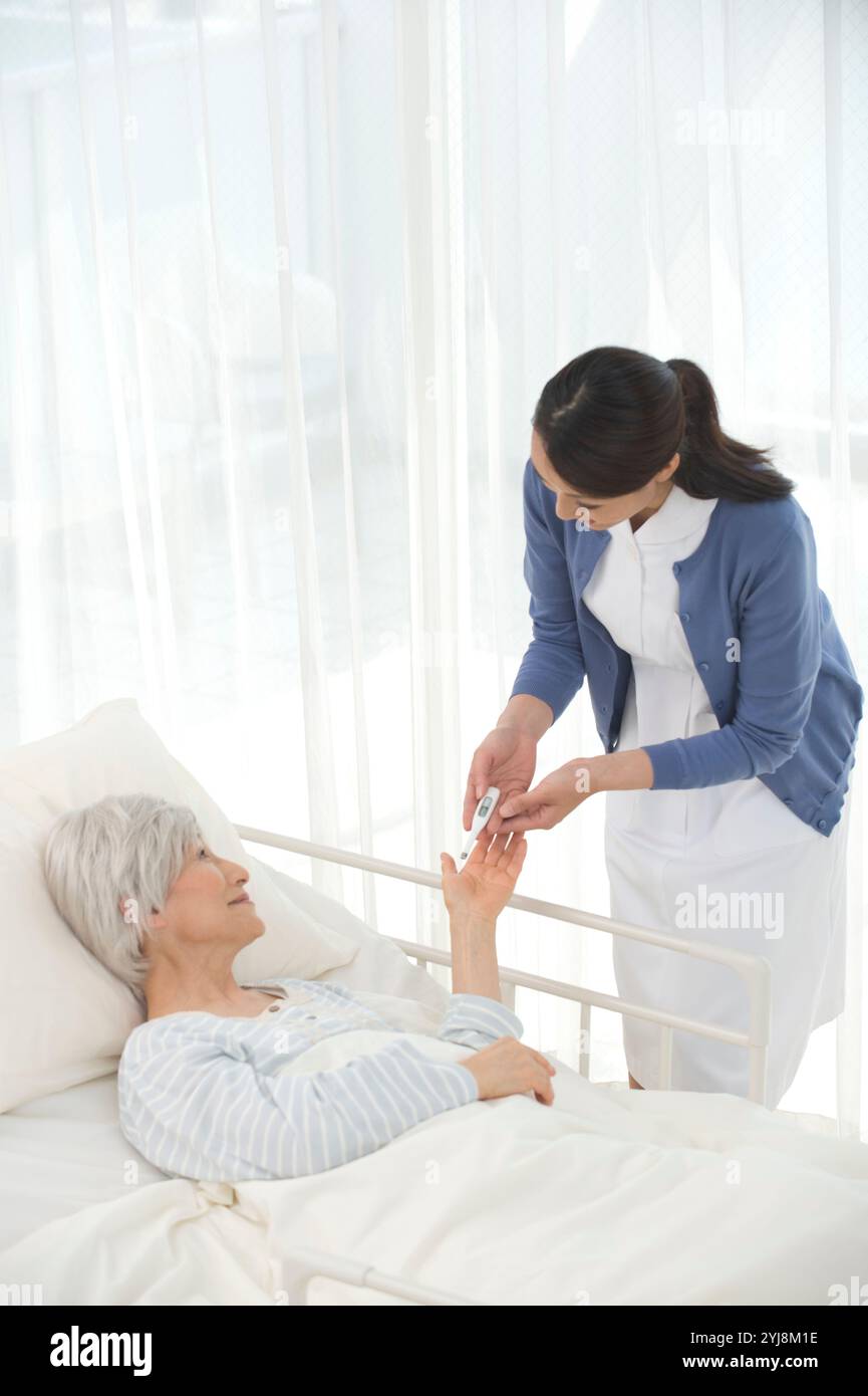 Nurse giving thermometer to hospital-bed old man Stock Photo - Alamy