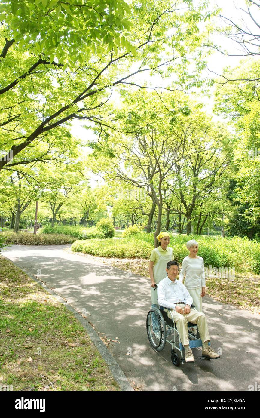 Elderly couple in wheelchair and care helper Stock Photo - Alamy