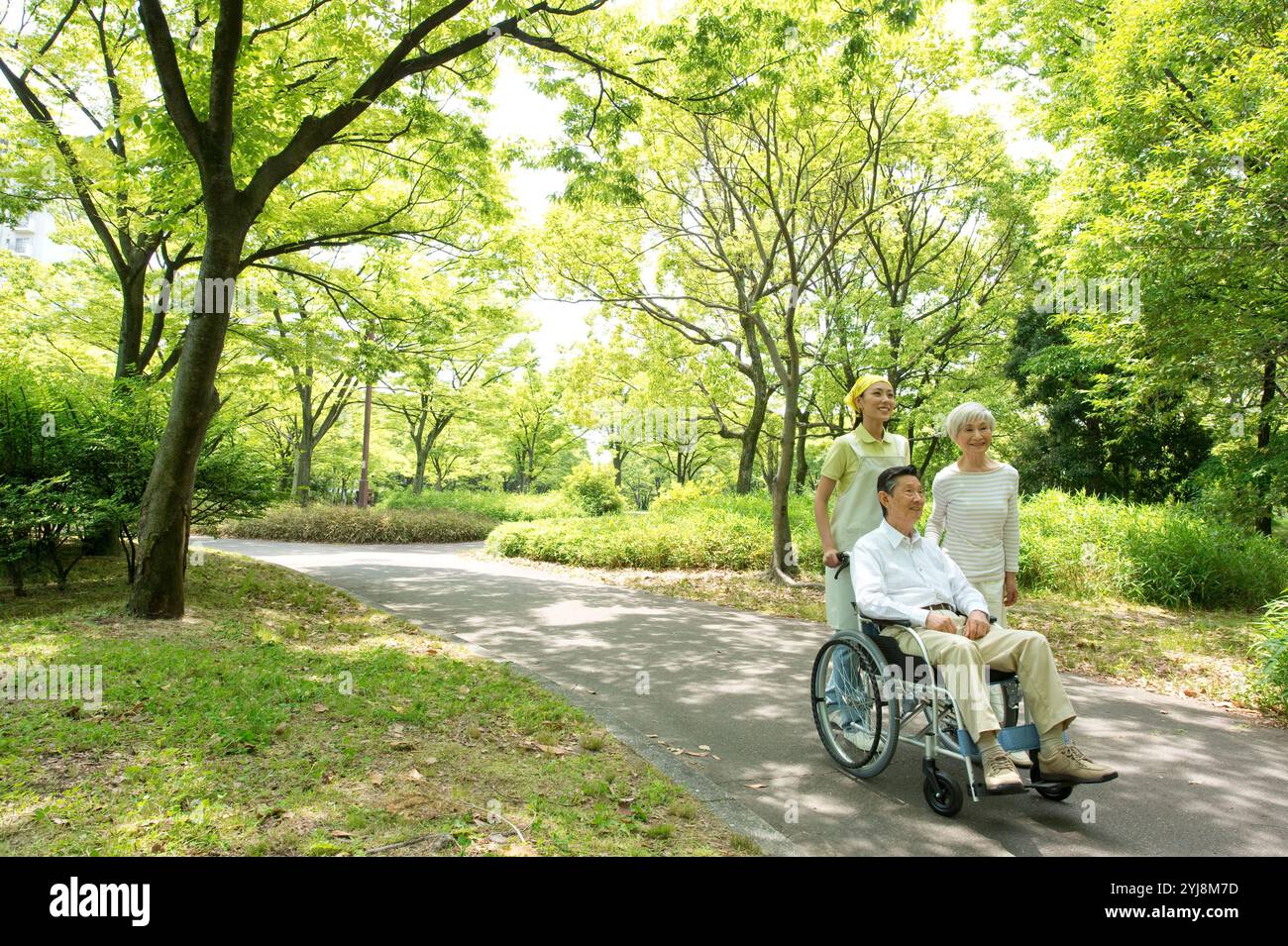 Elderly couple in wheelchair and care helper Stock Photo - Alamy