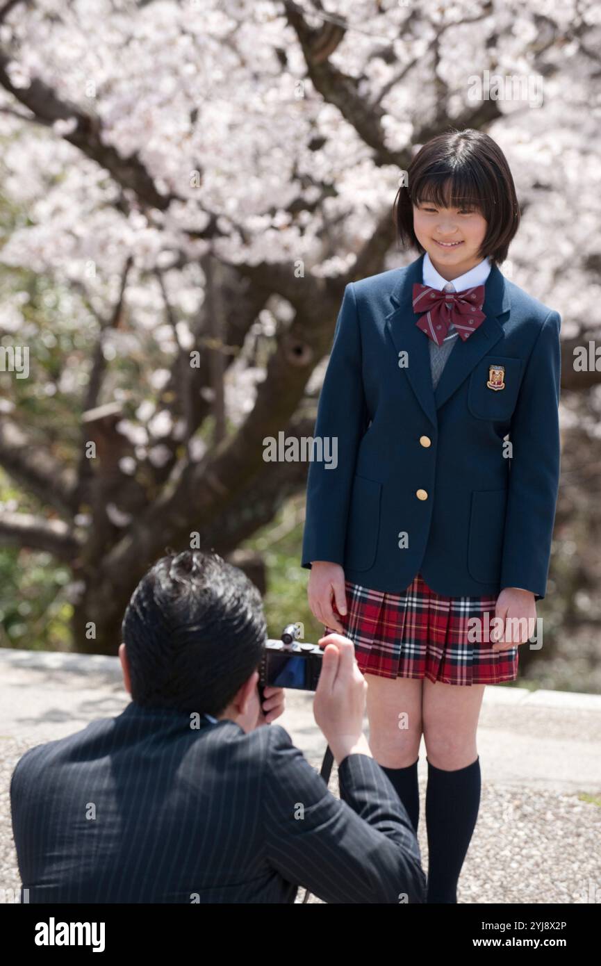 Father taking a photo of cherry blossoms and his high school girl ...