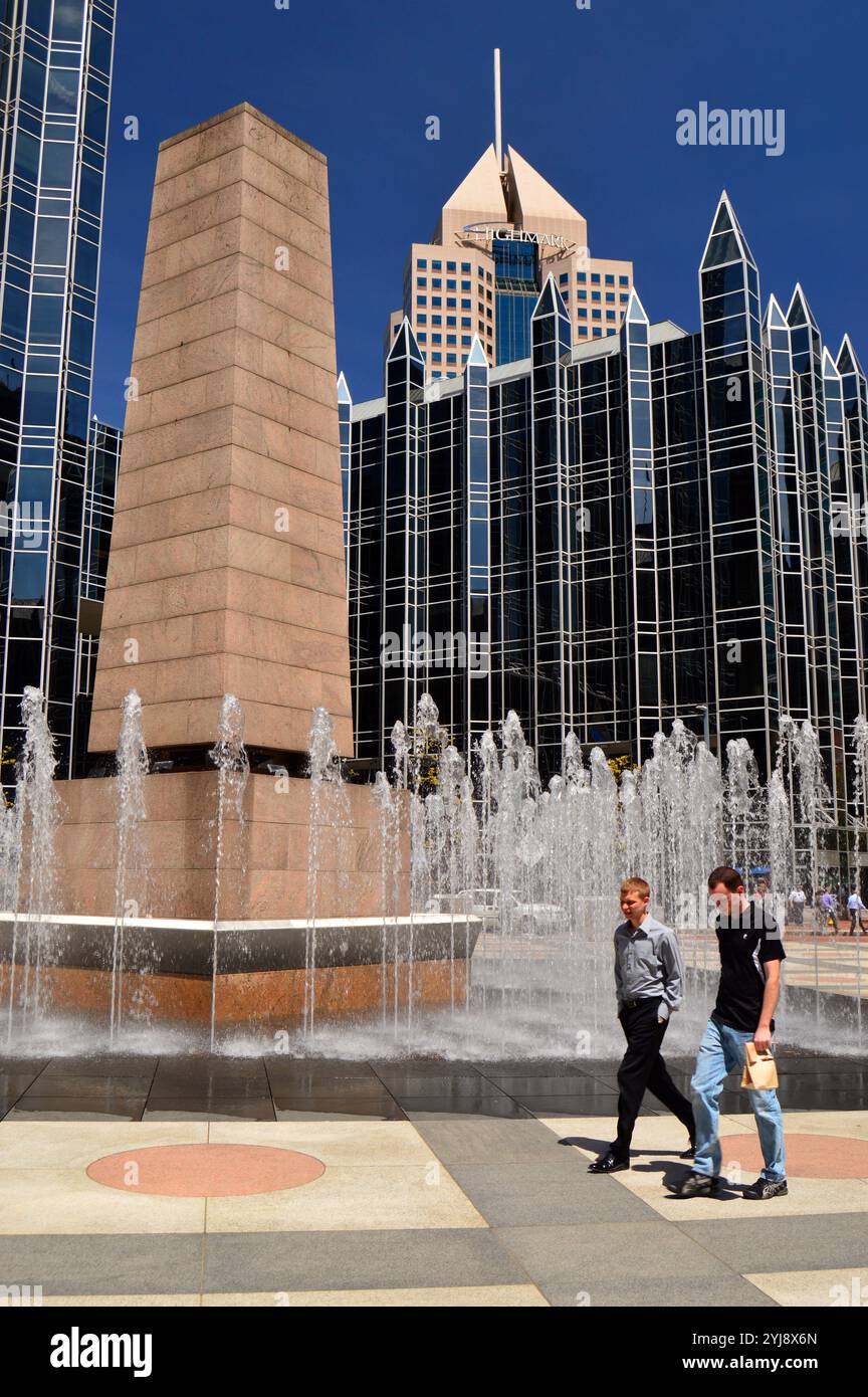 Two workers walk around the fountains and obelisk of the PPG Plaza at ...
