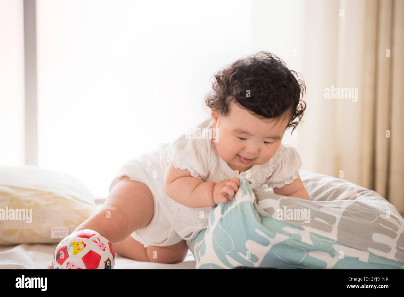 Six-month-old baby showing interest in cushion while crawling Stock ...