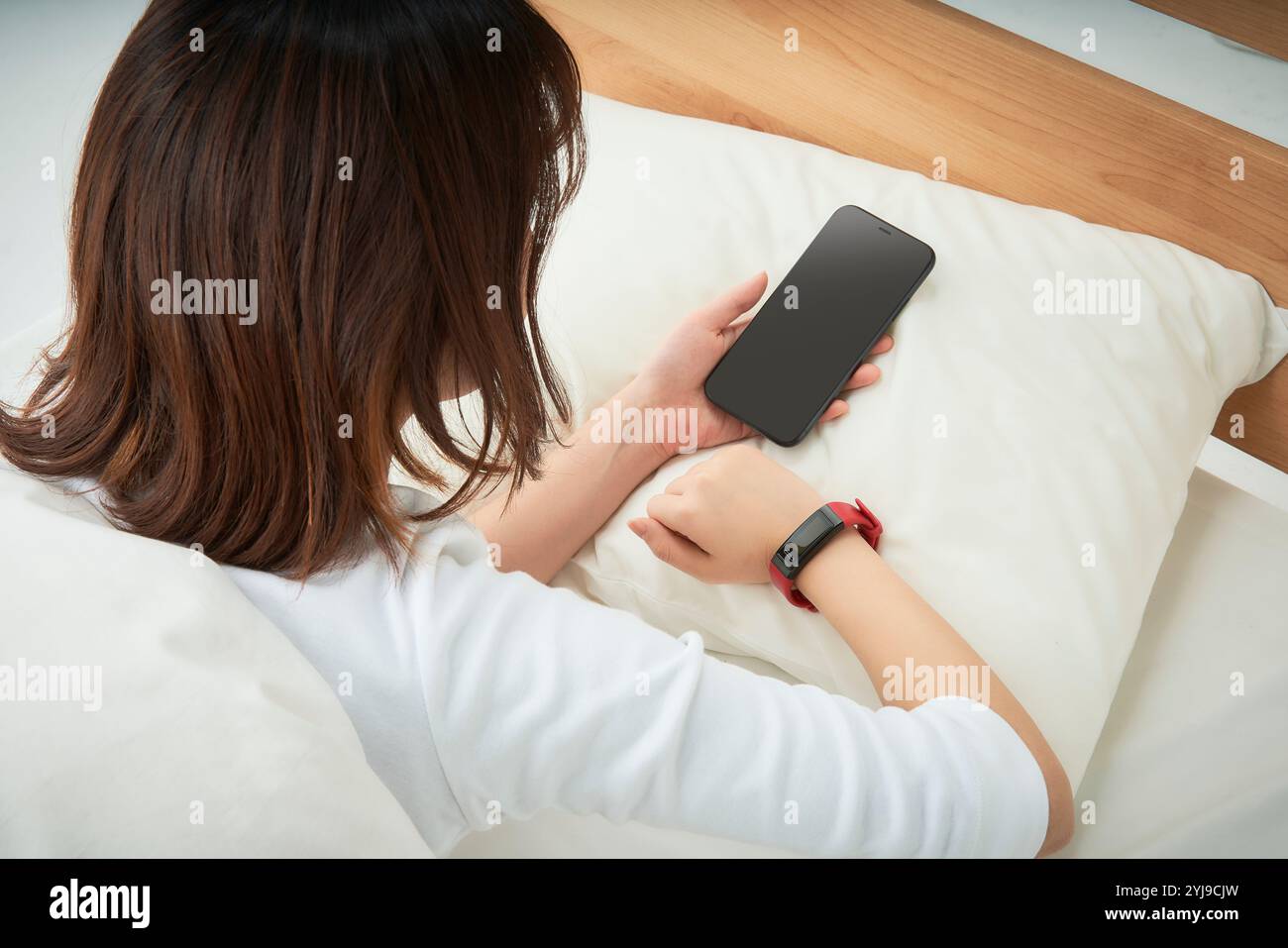 Woman linking her smartwatch to her smartphone before going to bed ...