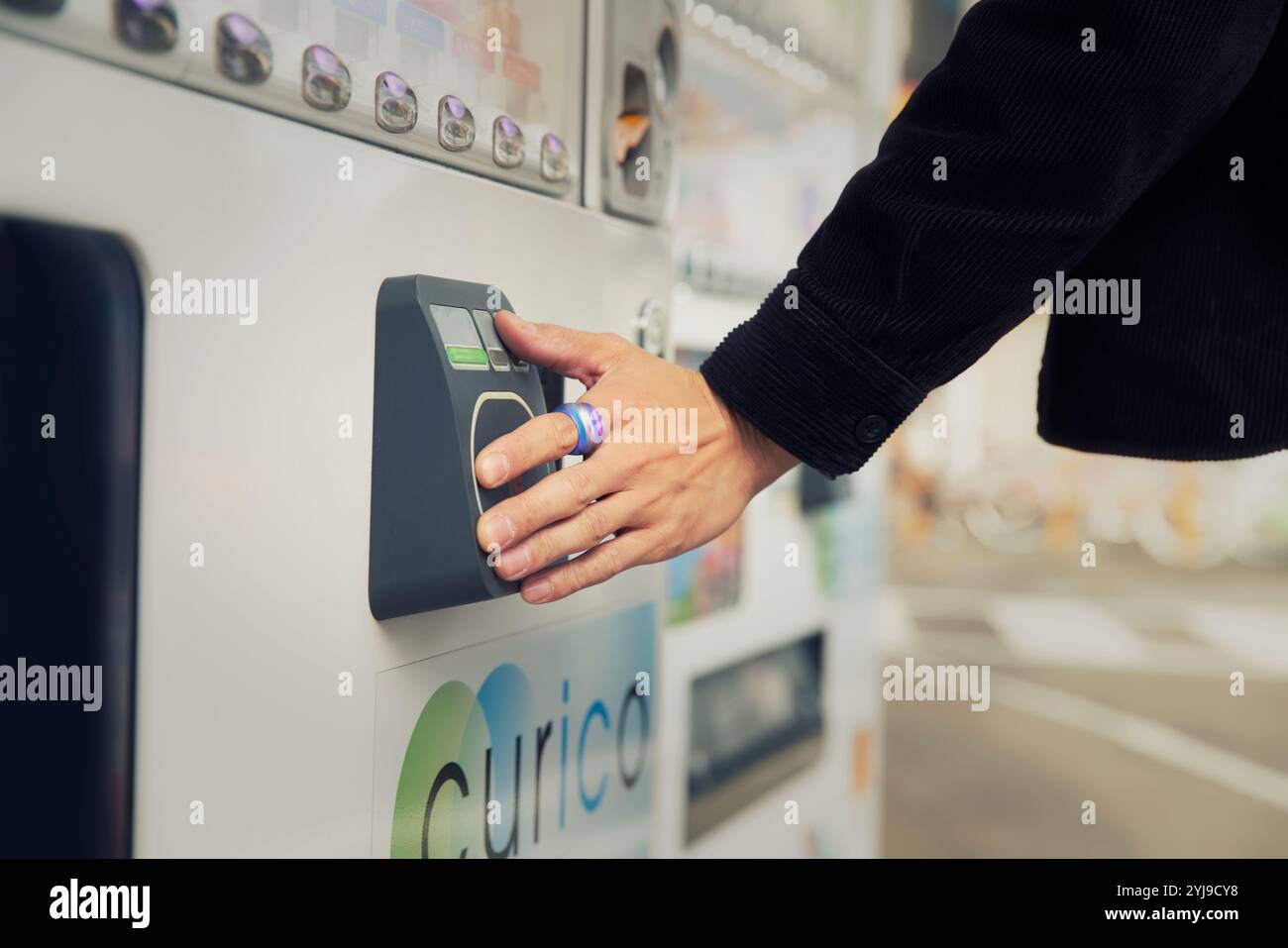 Hand of a man holding a smart ring over the card reader of a vending ...