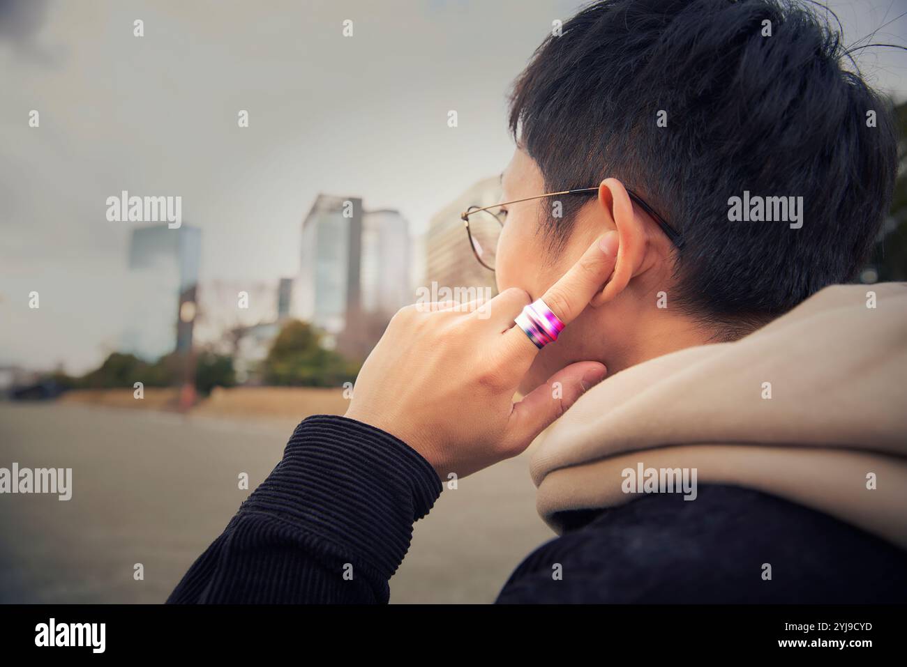 Man holding finger with smart ring to ear Stock Photo - Alamy
