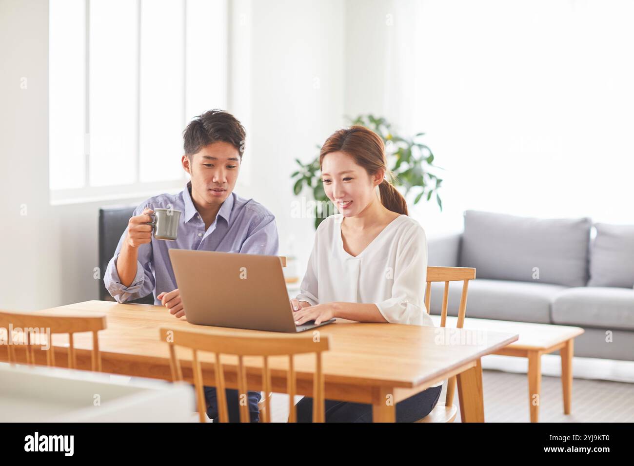 Couple watching computer in dining room Stock Photo - Alamy