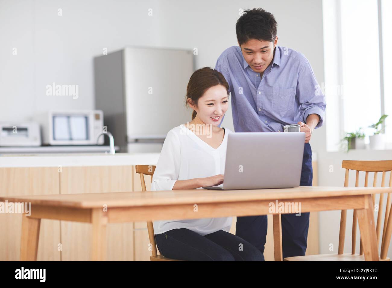 Couple watching computer in dining room Stock Photo - Alamy
