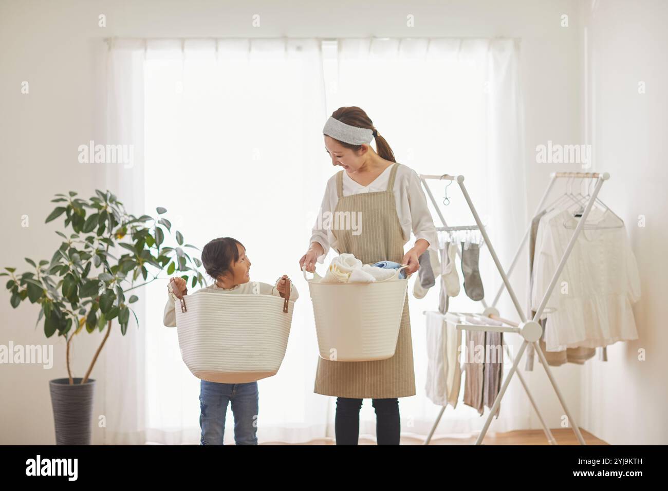 Parent and child drying laundry in living room Stock Photo - Alamy