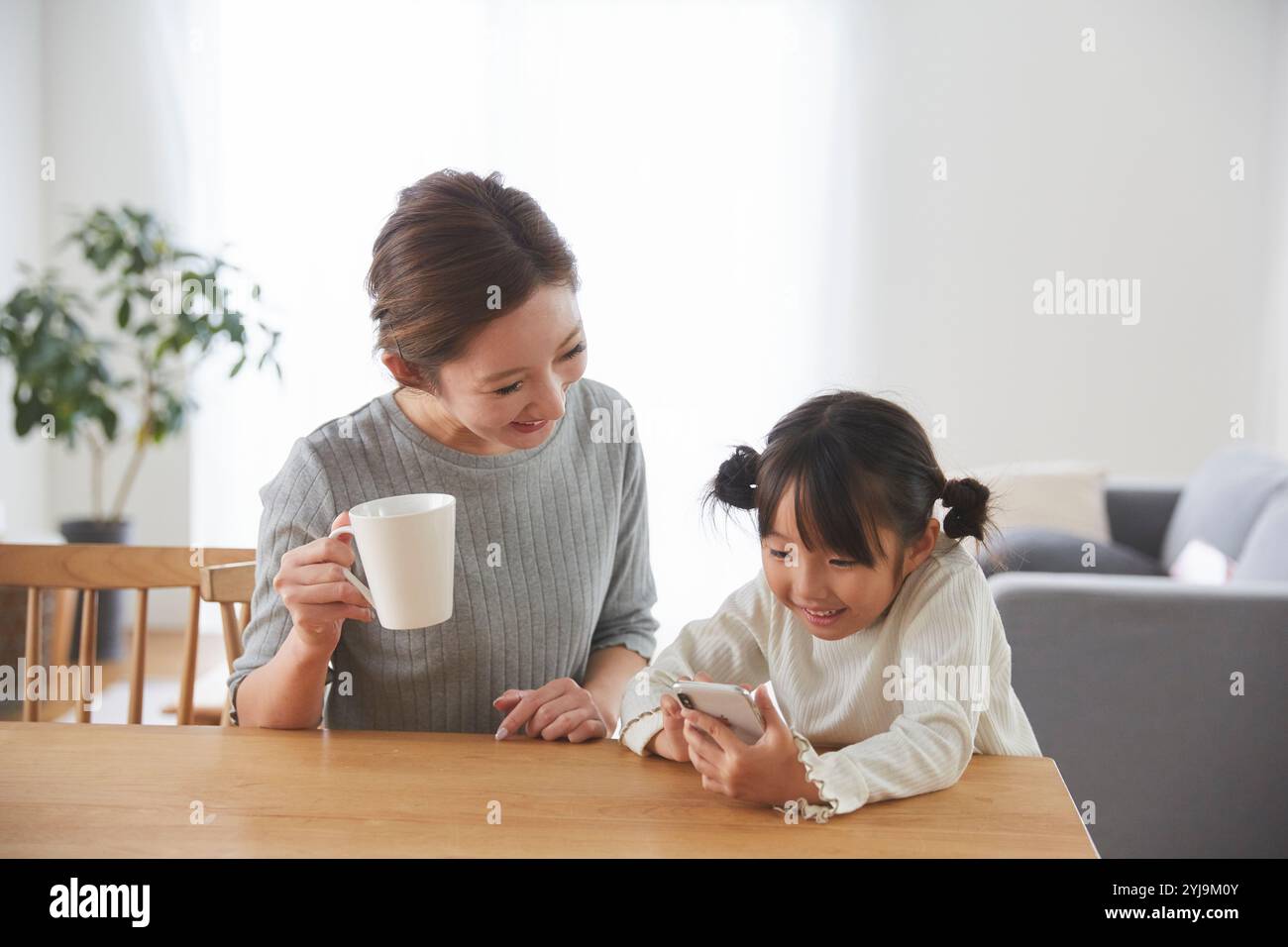 Parent and child touching their smartphones in the dining room Stock ...